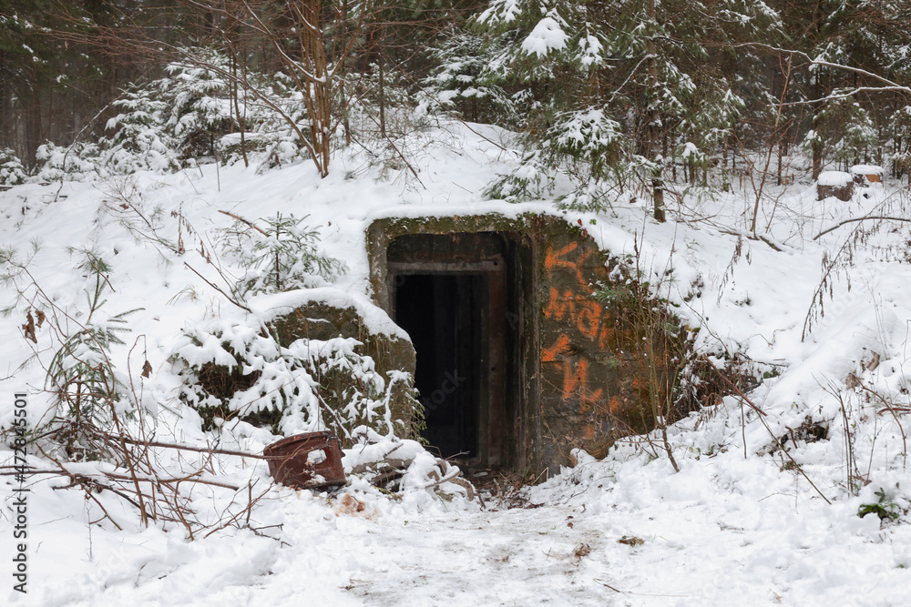 An abandoned, destroyed concrete bunker with an embrasure in a winter ...