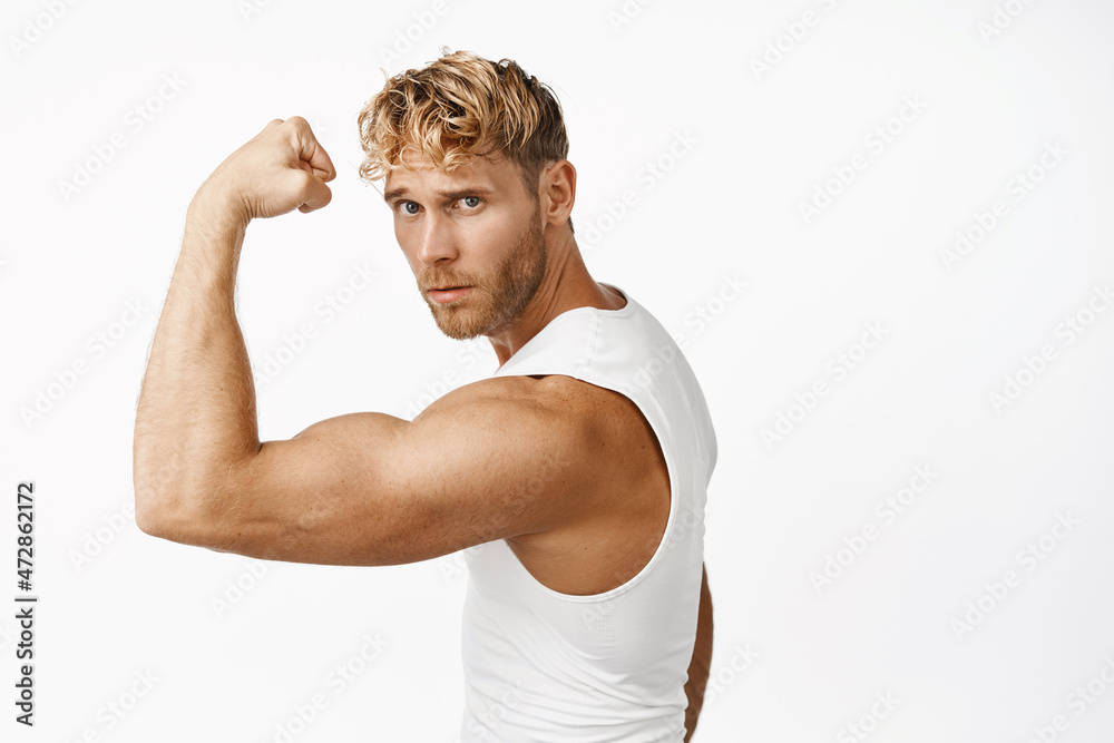 Portrait of handsome strong male athlete, fitness instructor flexing ...