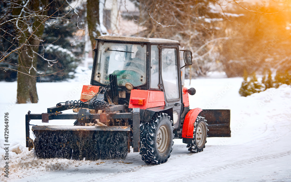 Tractor clear sidewalk from snow and ice after blizzard. Tractor with ...