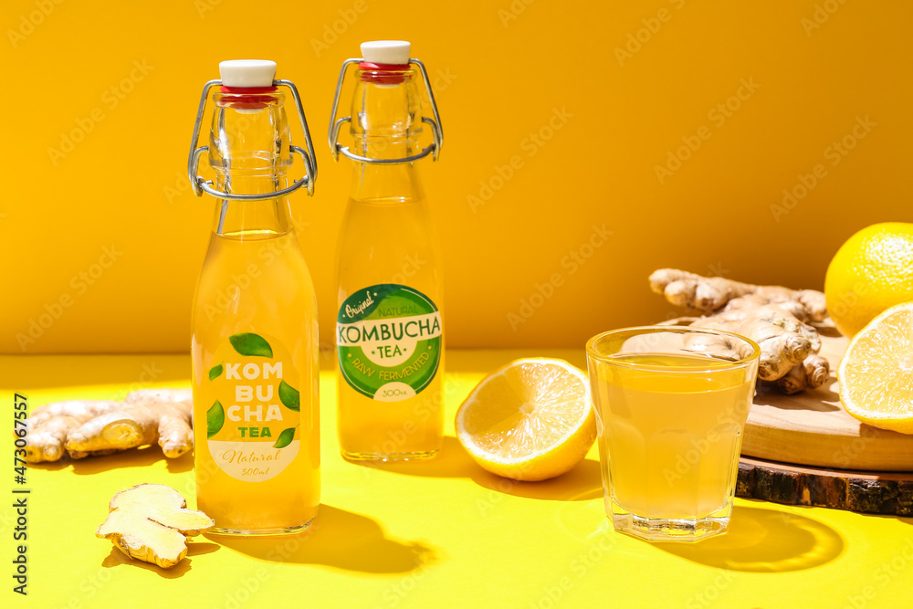 Glass and bottles of fresh kombucha on color background Stock Photo ...