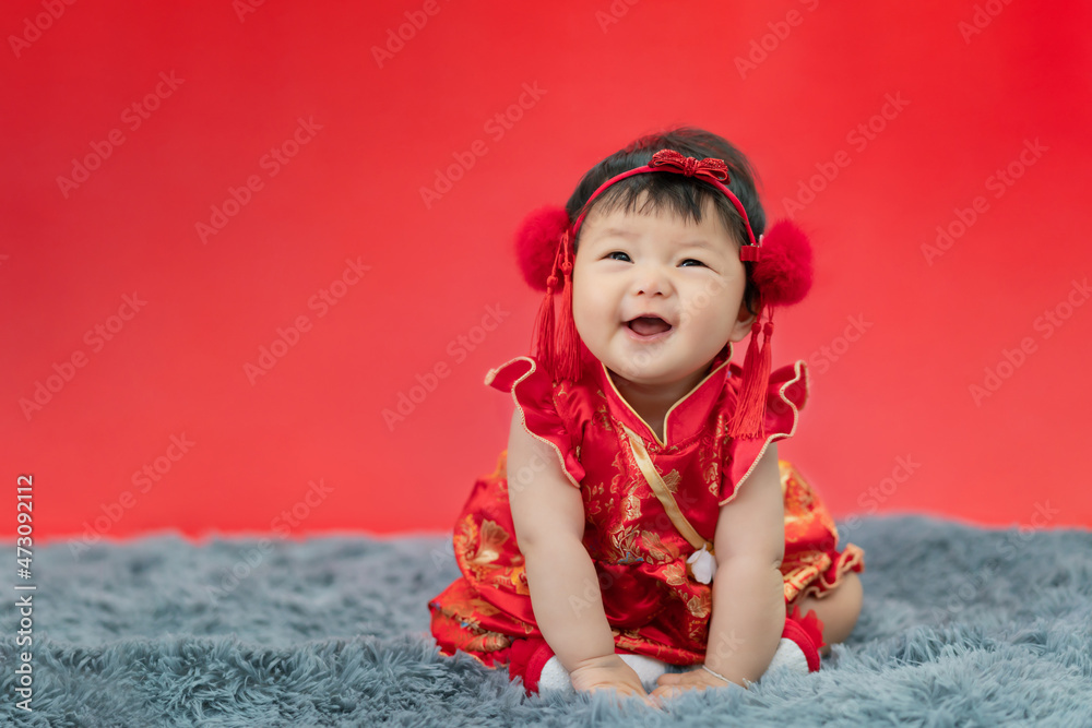 Asian Chinese baby girl sitting, smiling and laughing on carpet as red ...
