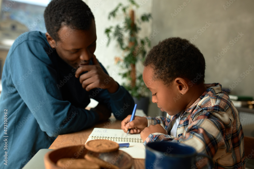 Fotografia do Stock: Diligent cute little boy with dark skin writing ...