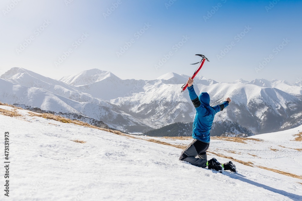 Man hiker with pickax in success pose in Polish Tatra mountains, winter ...