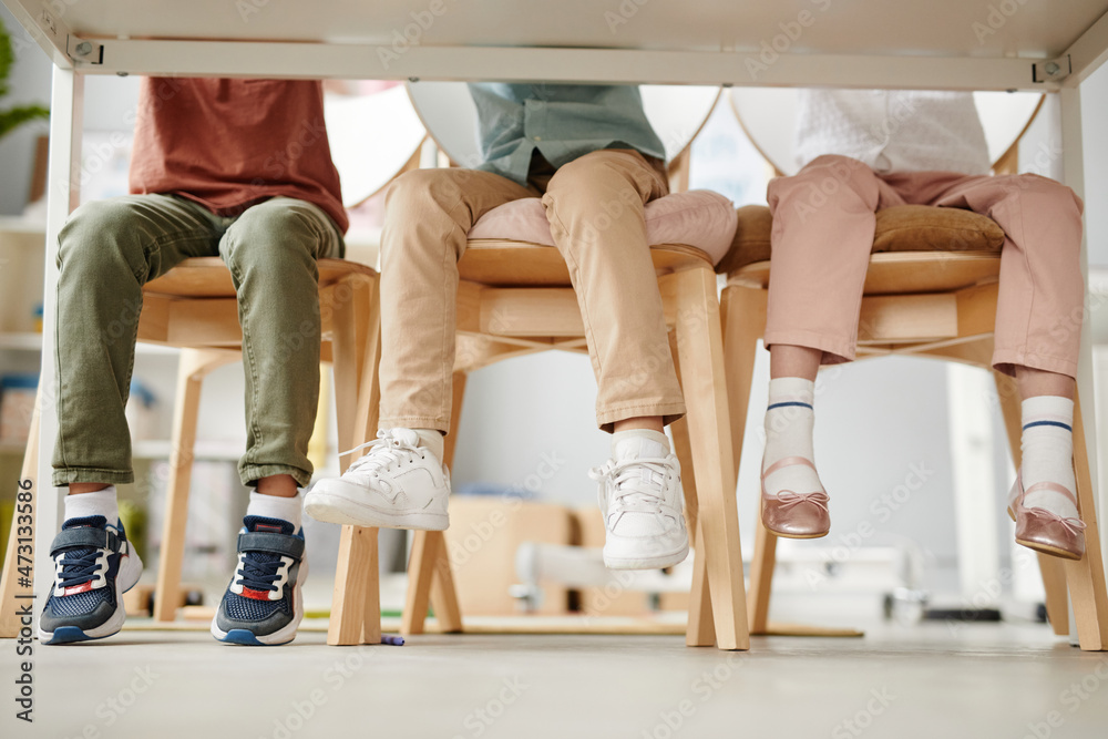 Group of school children sitting on chairs at desk during a lesson in ...