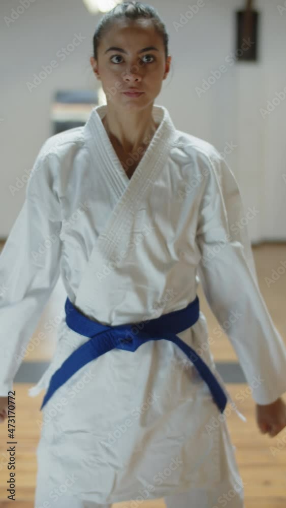 Vertical shot of focused girl showing defending karate poses. Front ...