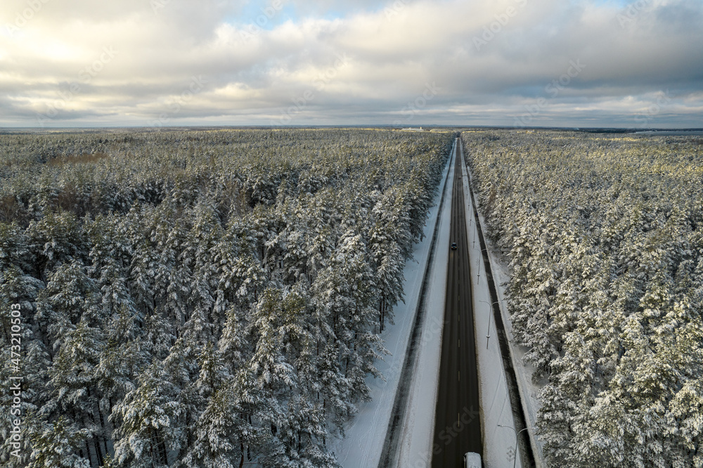 Aerial view of asphalt highway leading through frosty winter forests ...
