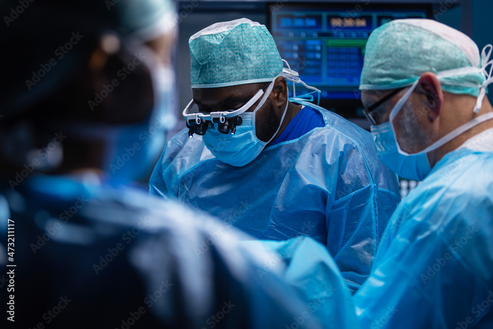 Multiracial team of professional medical surgeons performs the surgical ...