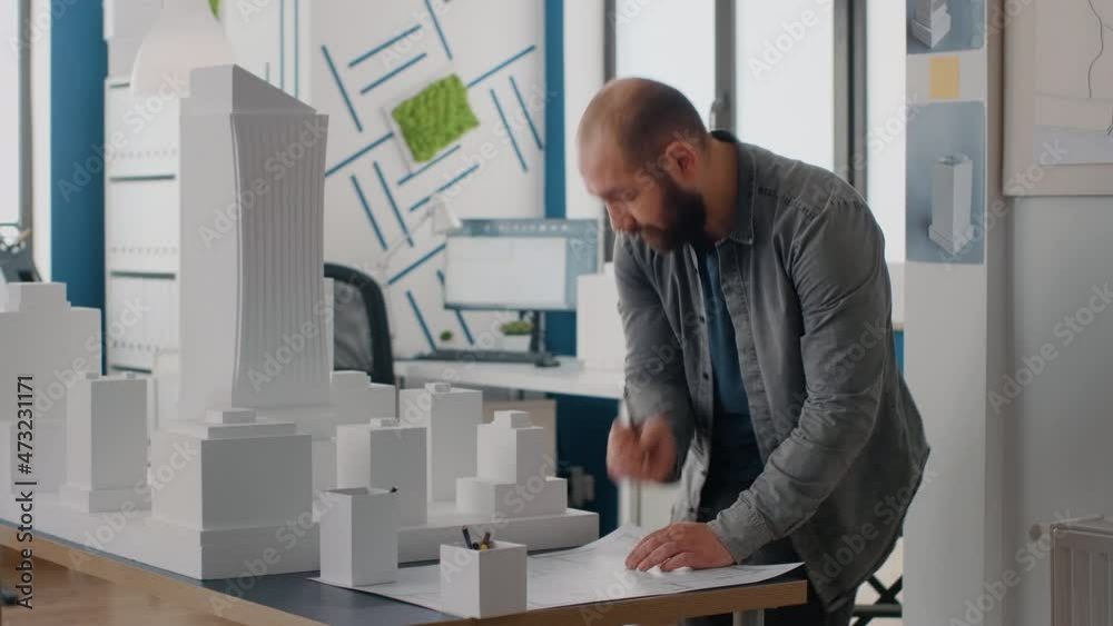 Man engineer analyzing building model to design blueprints plans on ...