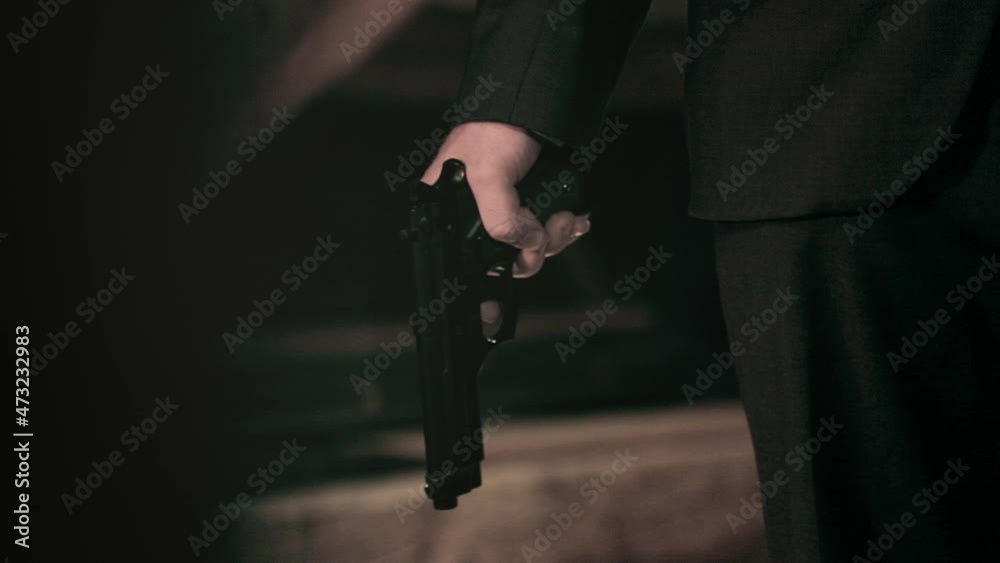 Mysterious mafia agent man in black suit holding pistol by torso. Pan ...