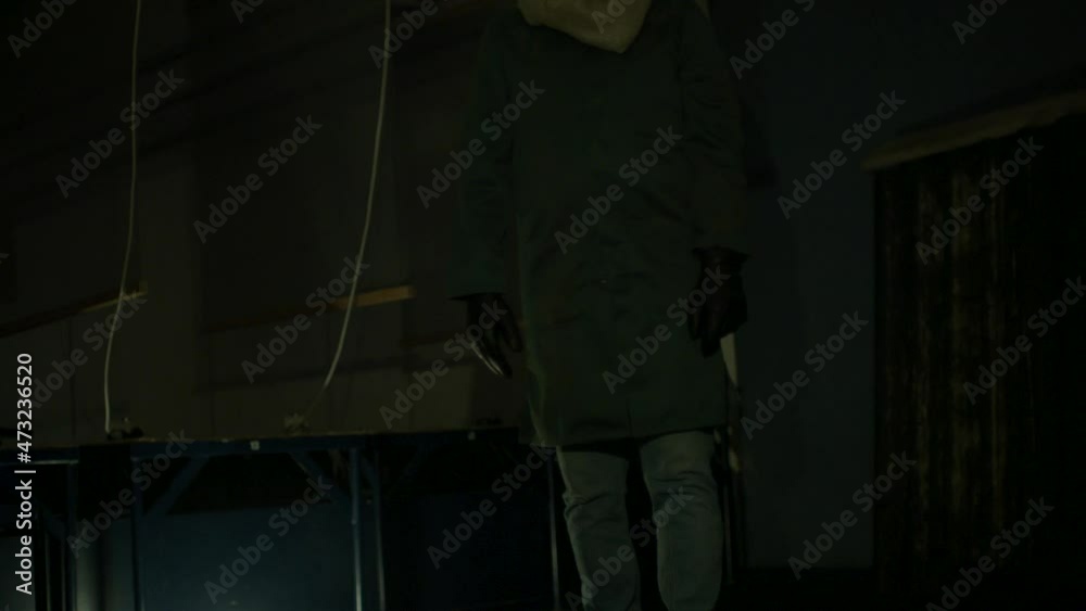 Tilt up of Serial killer wearing a burlap sack walking towards camera ...