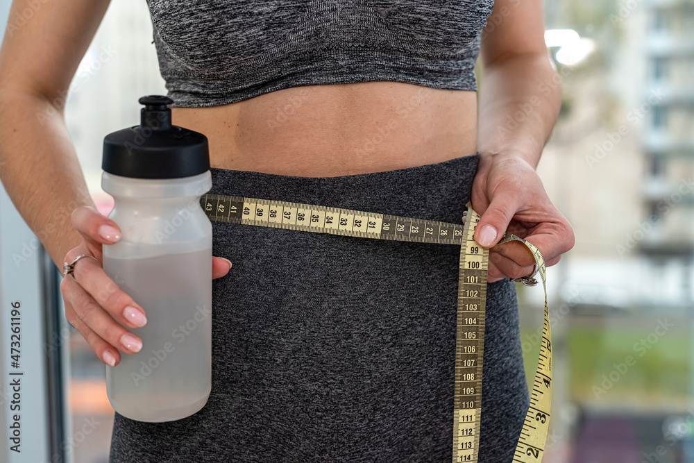 girl with a flat stomach measures the waist circumference with a ...