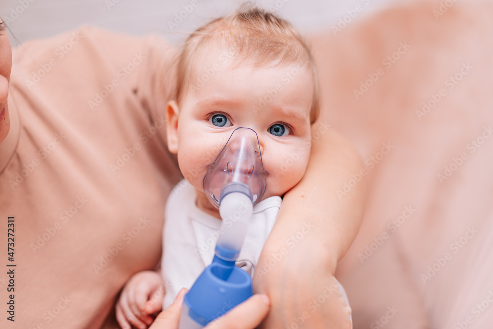 Foto de A little girl inhales from an inhaler with a nebulizer at home ...