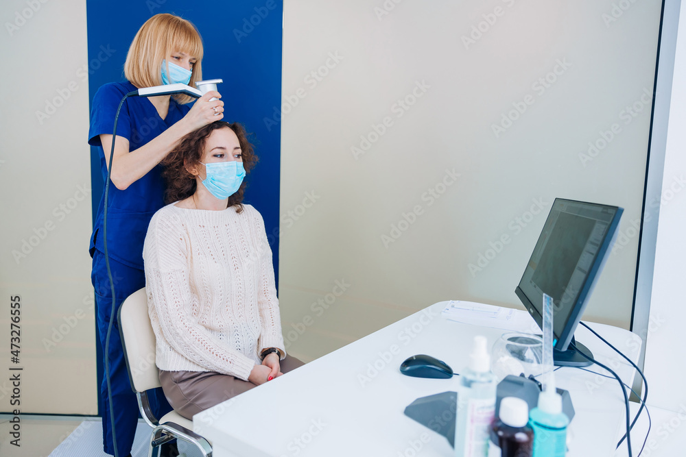 Hair and scalp diagnostics. Trichoscopy. The doctor examines the female ...