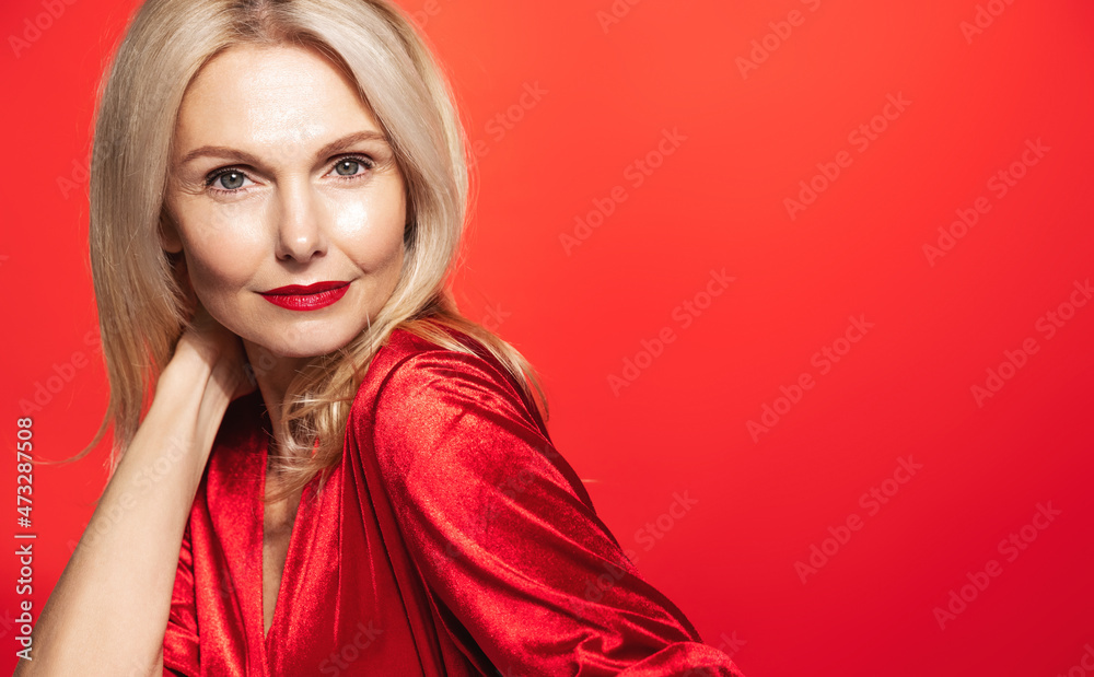 Stunning elegant woman, 55 years old, touches her healthy glowing hair ...
