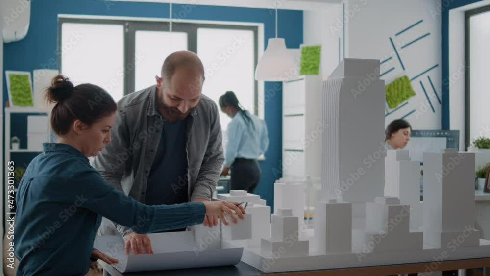 Man and woman analyzing blueprints plan and building model to design ...