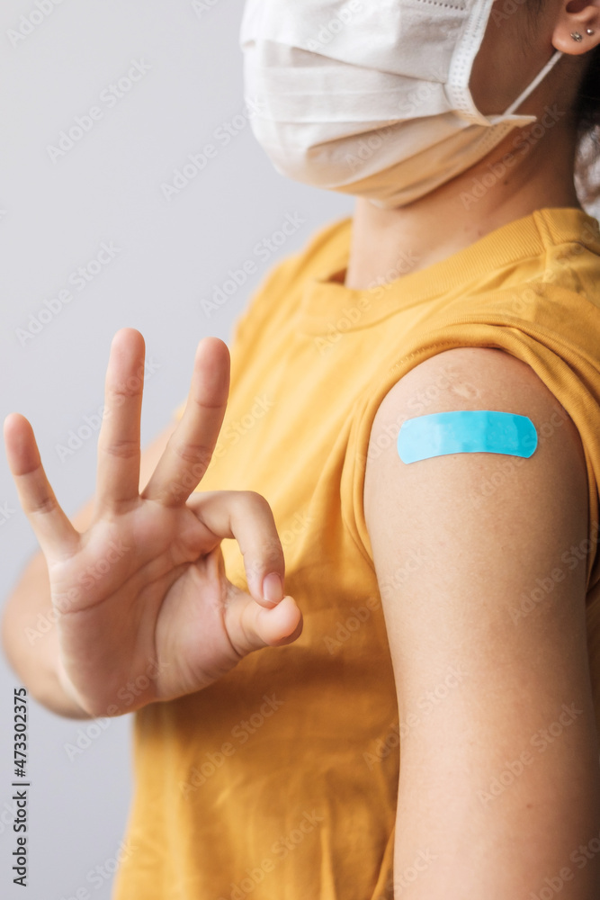 woman showing OK sign with bandage after receiving covid 19 vaccine ...