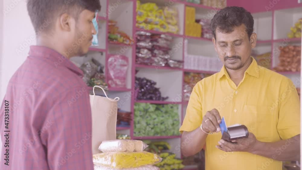 Indian customer making payment using credit card at groceries or Kirana ...