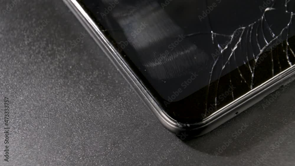 Broken smart phone rotates by with cracked screen in close up macro ...