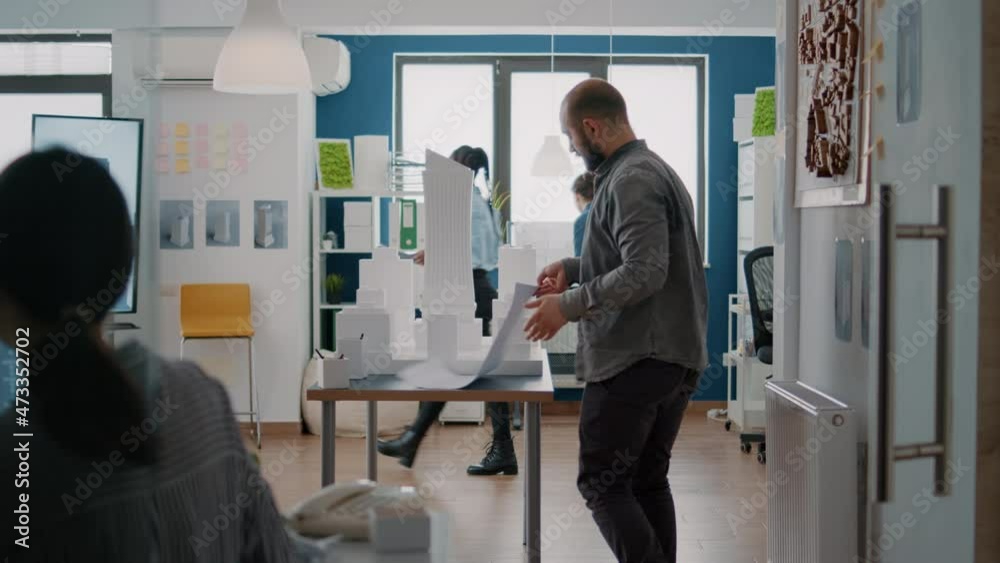 Man Analyzing Blueprints Plan And Building Model On Table To Design Construction Structure