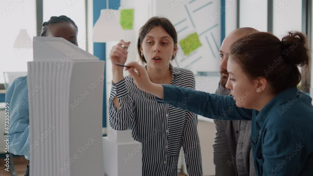 Close up of diverse people working with building model to design ...