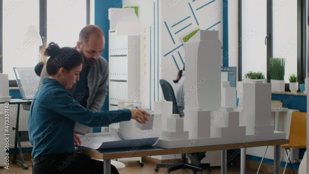 People working together to design blueprints plan with building model ...
