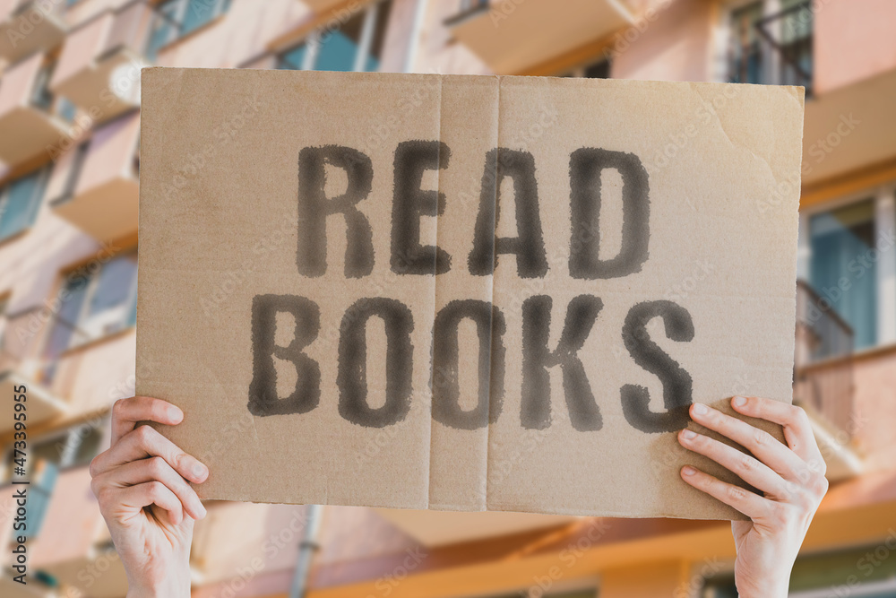 The phrase " Read books " on a banner in men's hand with blurred ...