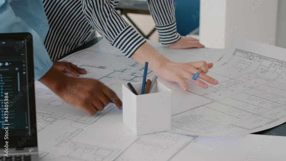 Close up of architects doing teamwork to design blueprints plans for ...