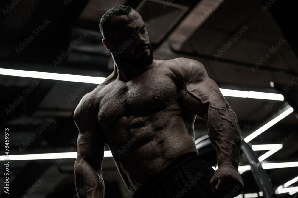 strong young bearded male with powerful bodybuilder body in dark night ...