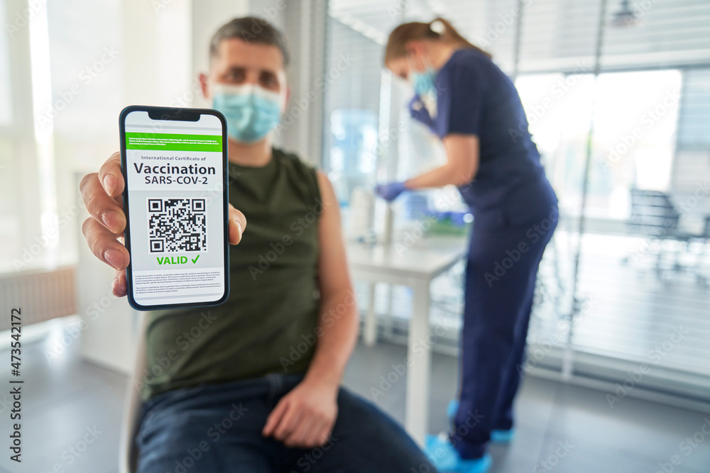 Man showing COVID-19 vaccination QR code on mobile phone while doctor ...