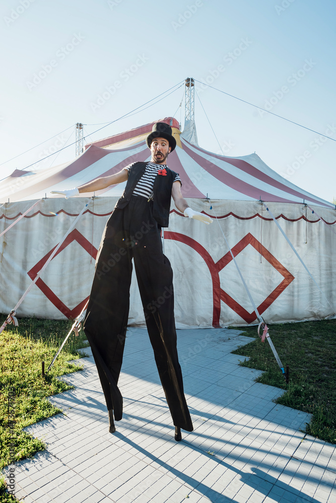 Male artist balancing on stilts in front of circus tent Stock Photo ...