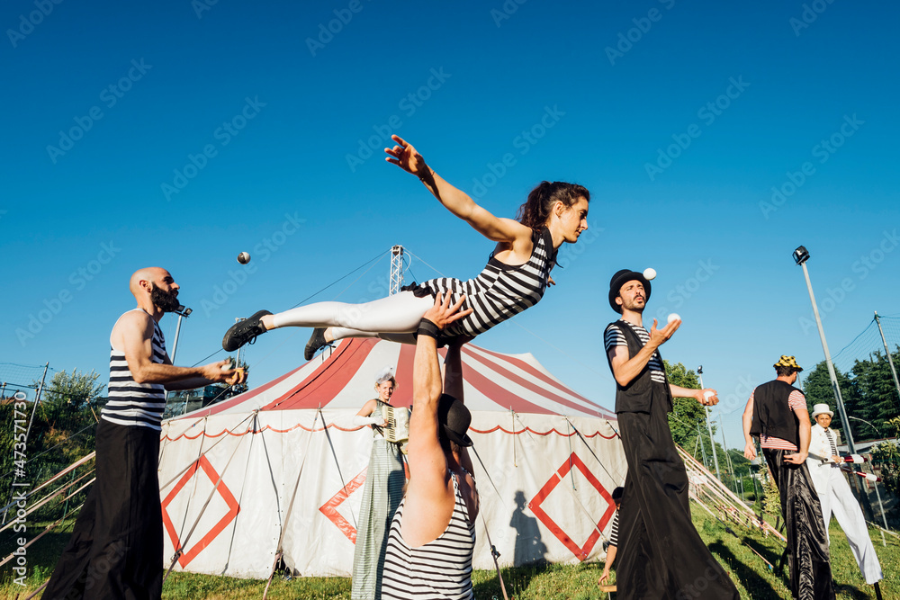 Male and female acrobats performing with artists in front of circus ...