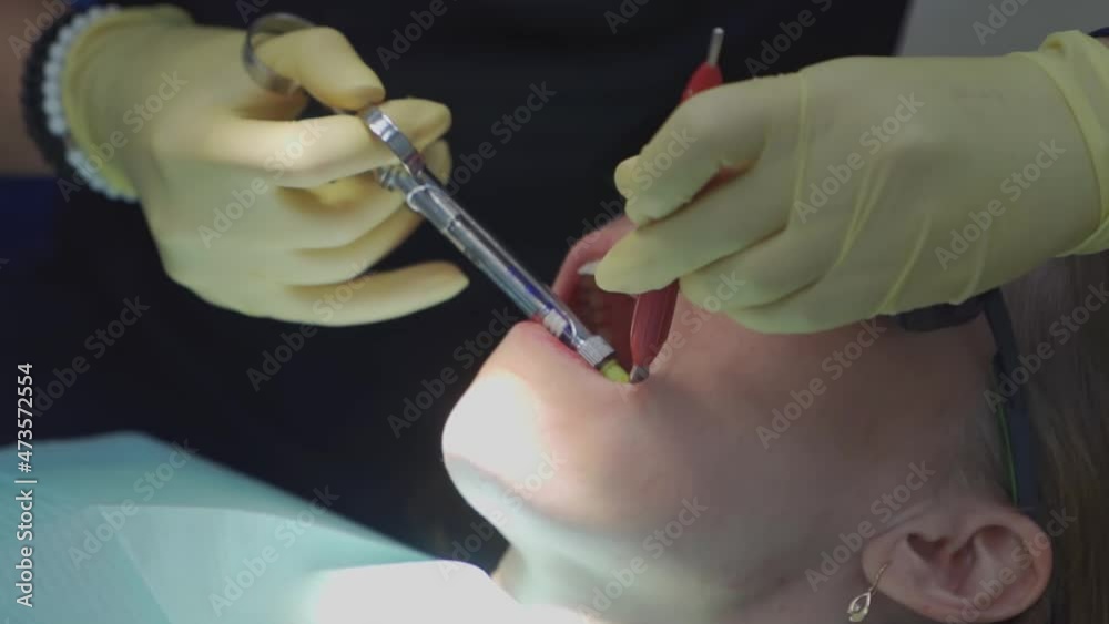 real. dentist injects an anesthetic into patient before tooth ...