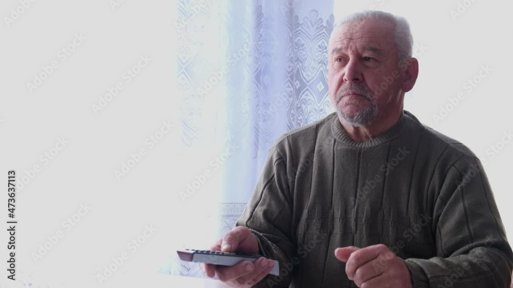 Gray-haired old man sitting on a sofa in the living room alone ...