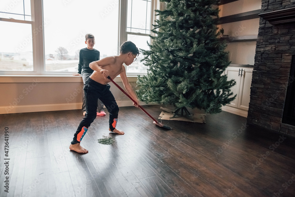 Shirtless boy using a broom to clean. Stock Photo | Adobe Stock