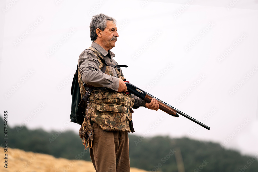 Mature hunting man holding a gun while searching for new preys. Stock ...