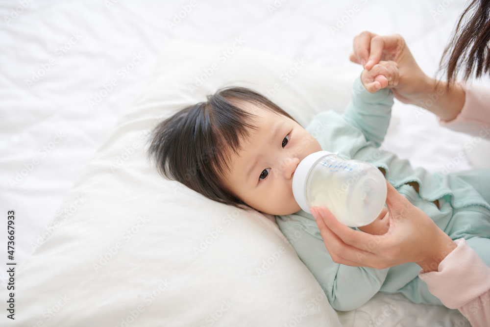 Cute little asian baby drinking from bottle Stock Photo | Adobe Stock