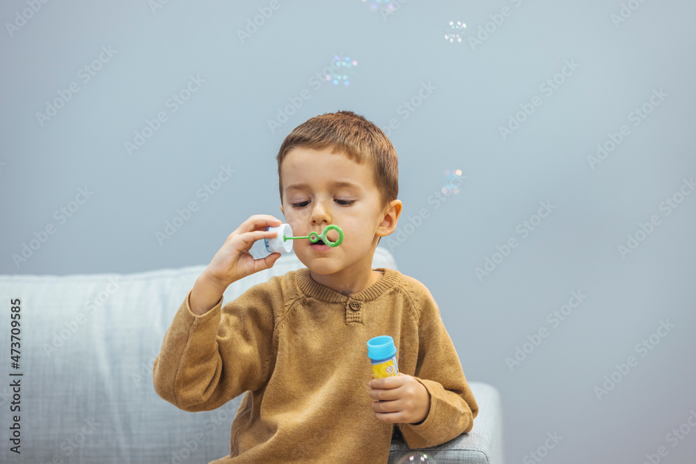 Happy little kid blowing soap bubble at home. Child indoor activity ...