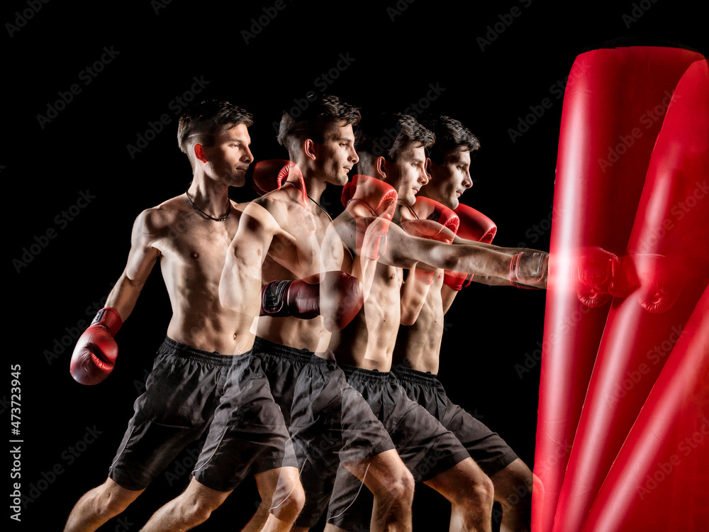 Young male boxer punching red bag against black background Stock Photo ...