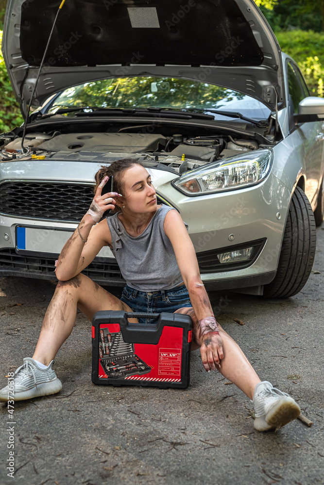 beautiful young dirty girl trying to repair her own car after a ...