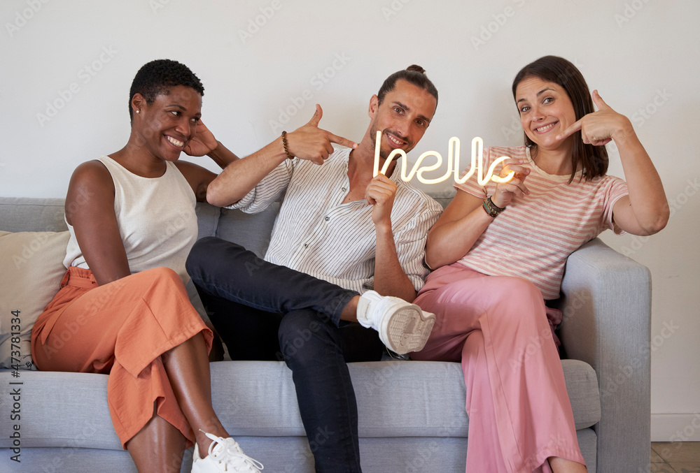 Happy male and female coworkers pointing at Hello sign illuminated text ...