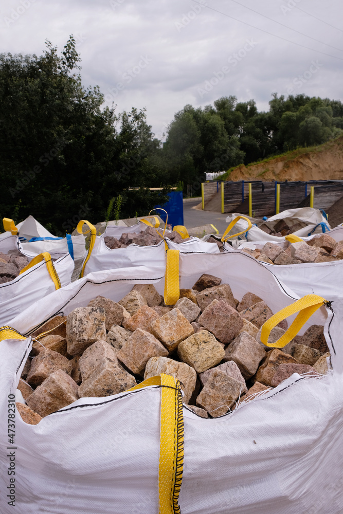 Beige cobblestones in polypropylene big bags with yellow tape slings ...