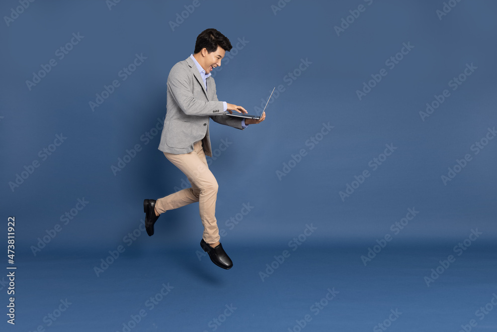 Young Asian business man jumping in air using laptop computer isolated ...