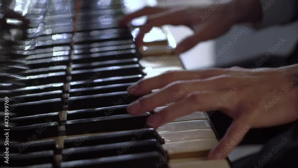 Pianist plays music on a grand piano. Musician at a concert or repetition. The man hands press ...