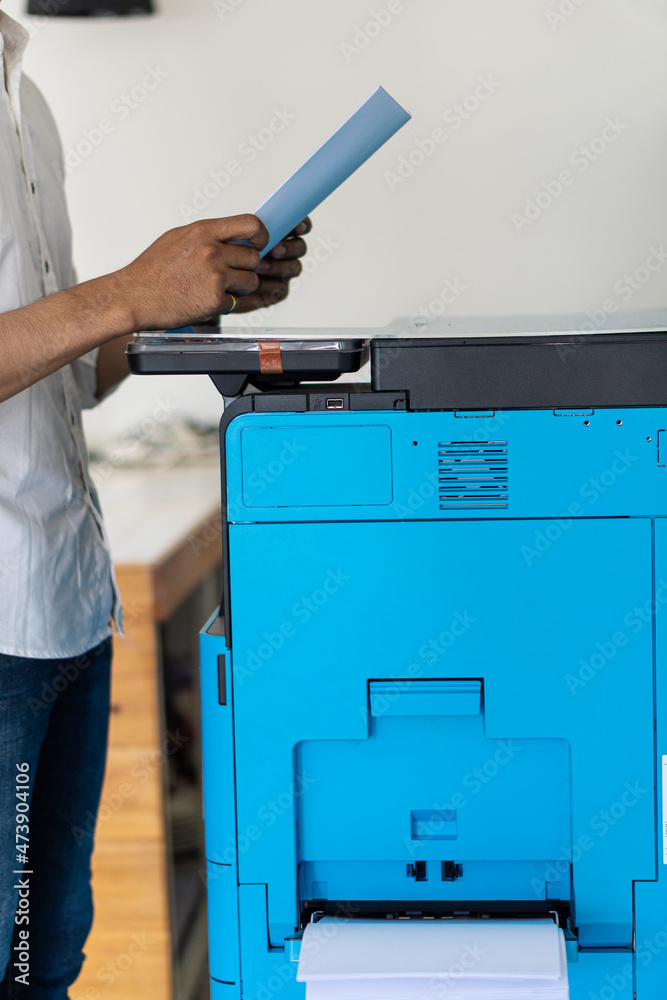 Young man holding a piece of paper and standing next to an office work ...