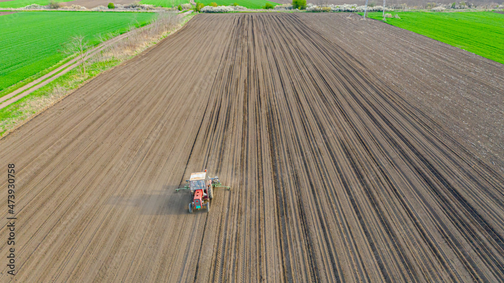 Aerial view of tractor as dragging a sowing machine over agricultural ...