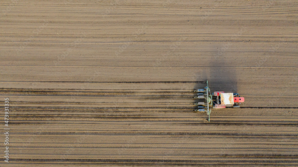 Aerial top view of tractor as dragging a sowing machine over ...