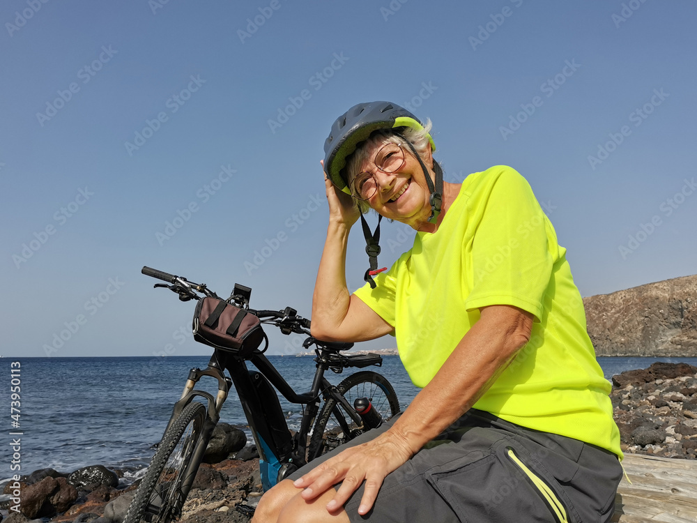 Senior biker woman outdoors at sea stop riding to rest enjoying freedom ...