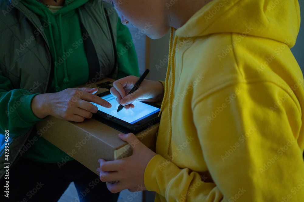 Boy signing on screen with digitized pen while receiving package Stock ...