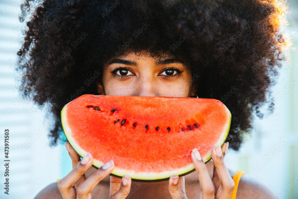 Afro woman covering face with slice of watermelon Stock Photo | Adobe Stock
