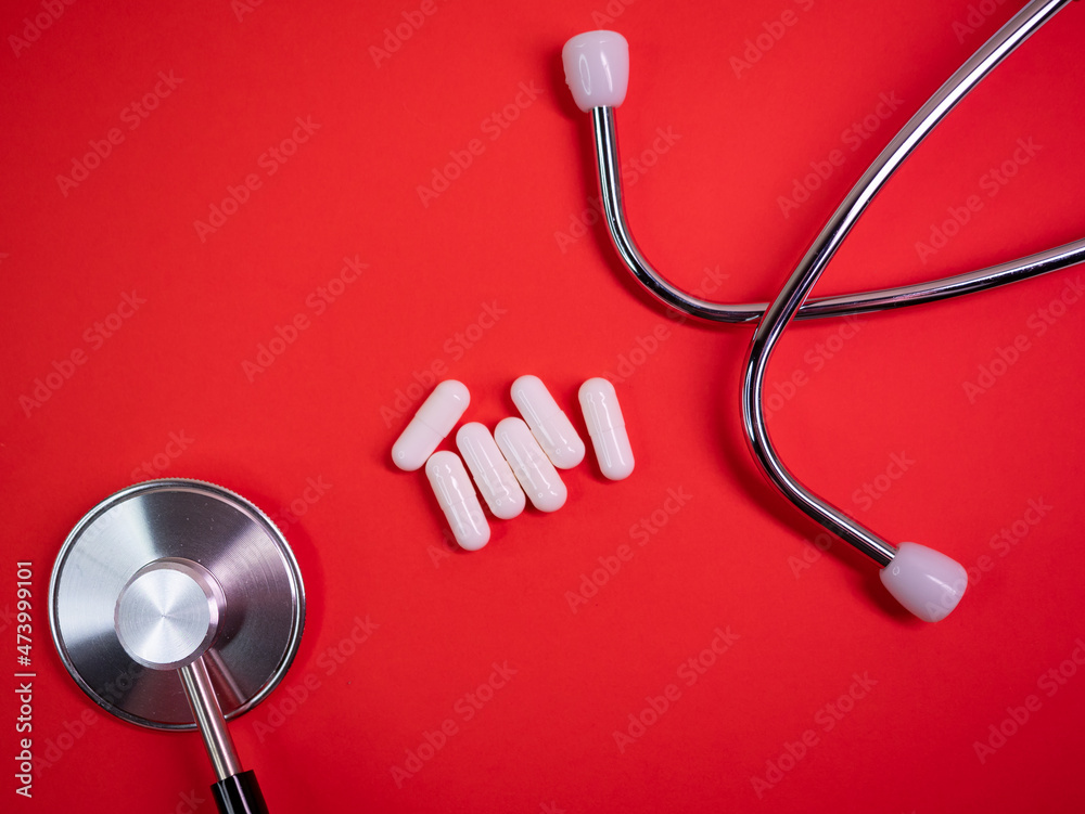 White drug capsules on colored red paper texture background. Macro ...